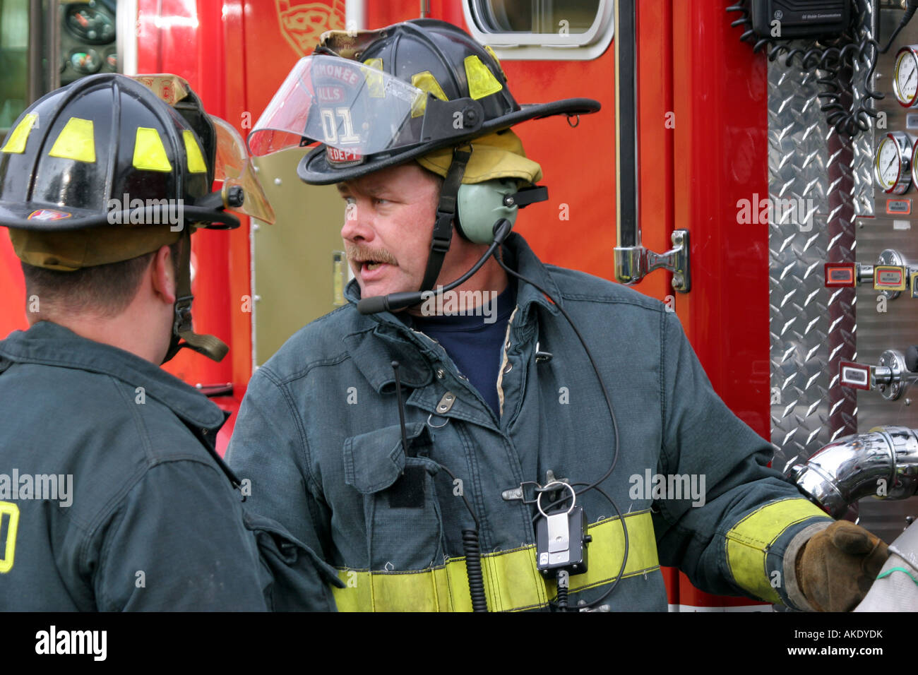 Two fire fighters talking at a fire emergency scene to supply water ...