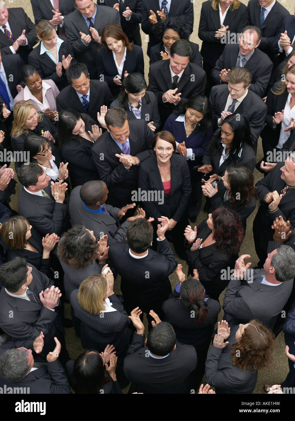 Large group of business people clapping, surrounding woman looking up ...