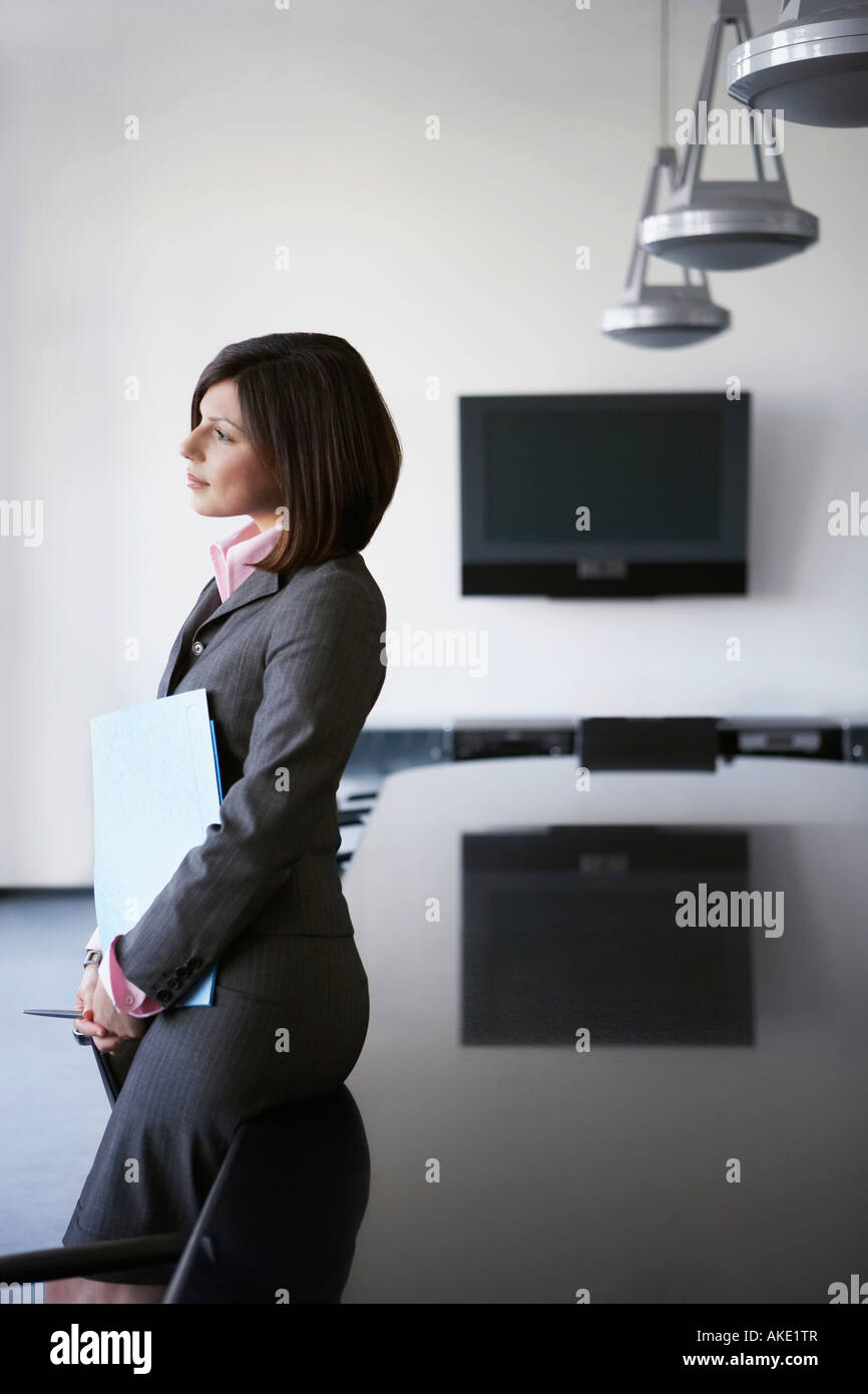 Business woman leaning against table in conference room Stock Photo - Alamy