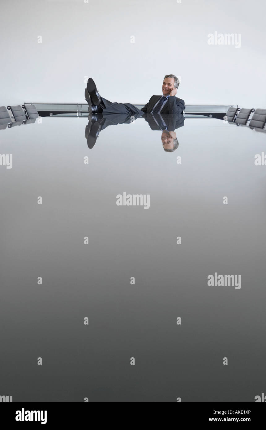 Business man with feet up on table in conference room Stock Photo - Alamy