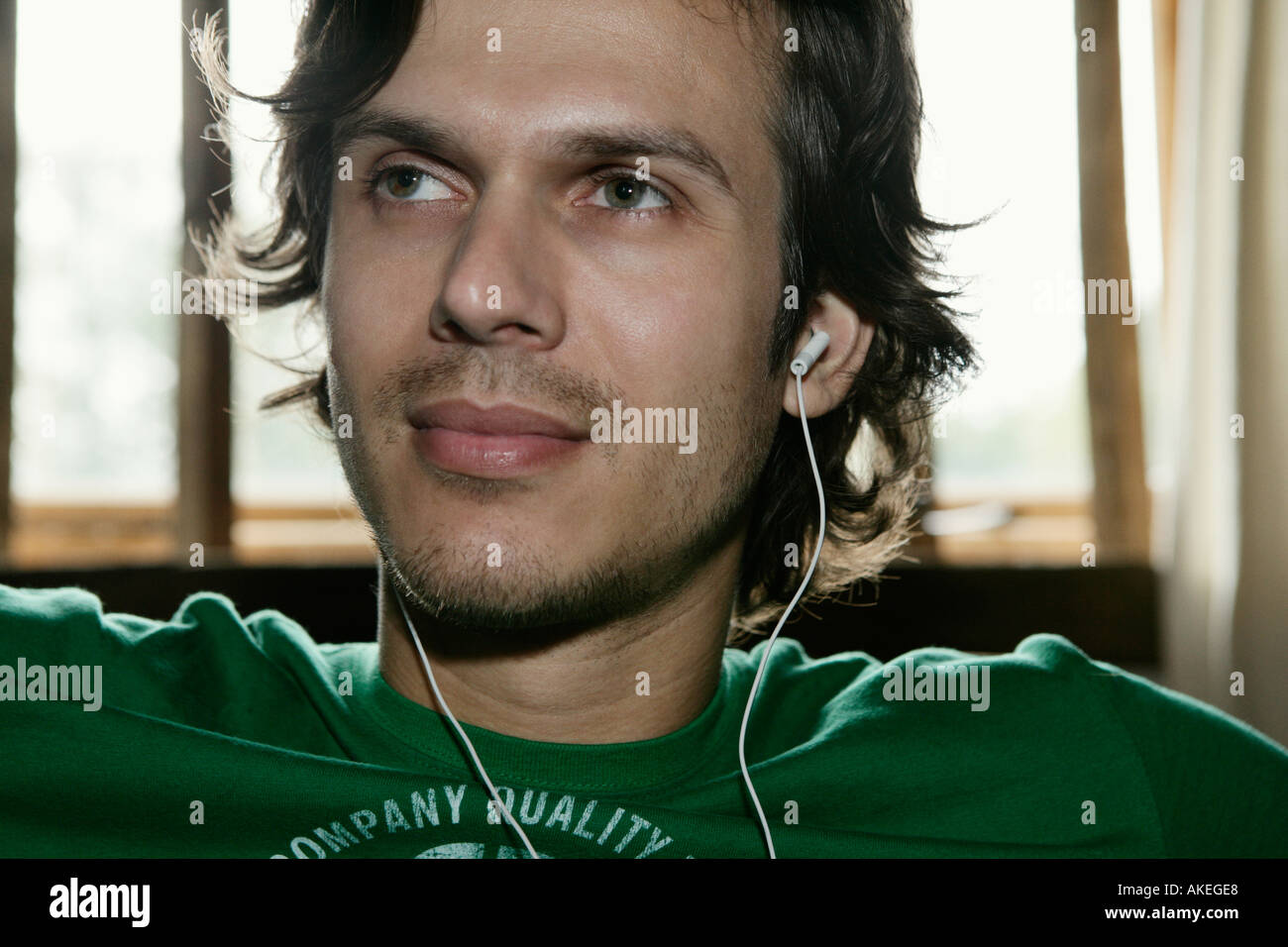 Man listening to music on small white headphones Stock Photo - Alamy