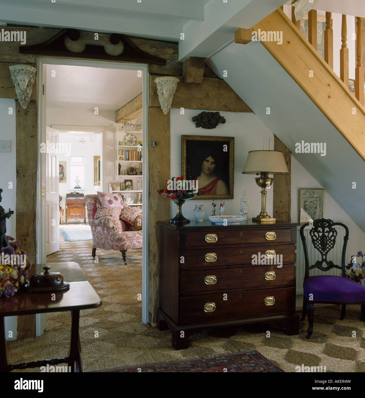 Antique chest of drawers below staircase in country hall with rush ...