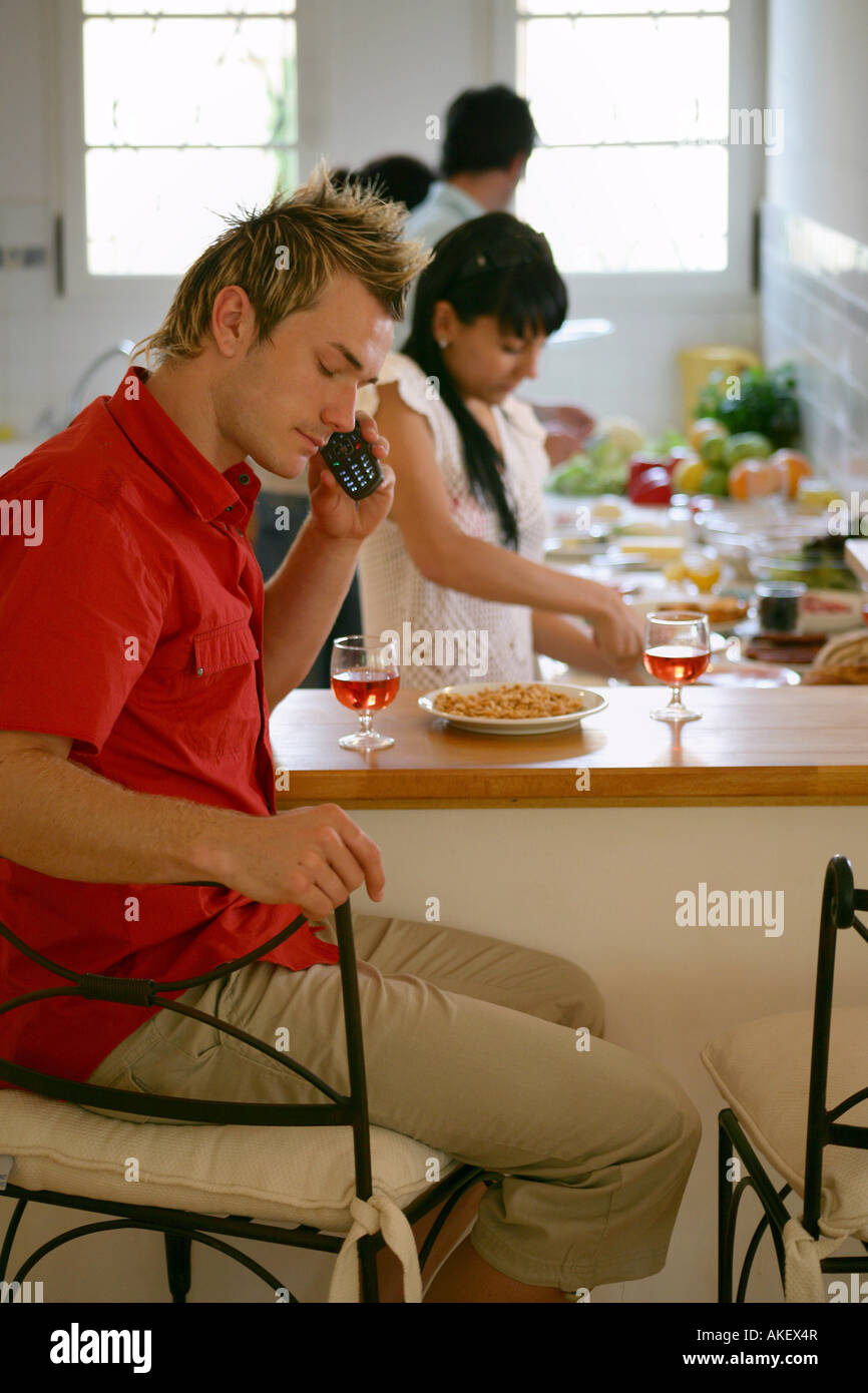 young man phoning while friends are cooking Stock Photo - Alamy