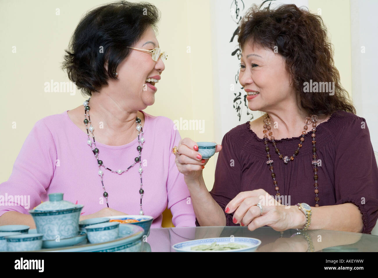 Two senior women sitting at a table and looking at each other Stock ...