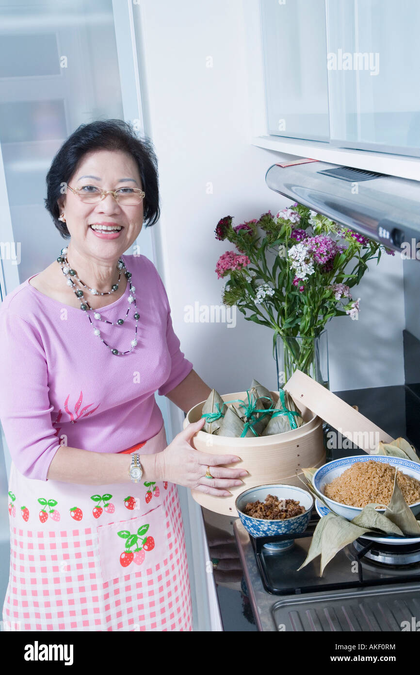 Portrait of a senior woman holding dumplings in a bamboo steamer Stock ...