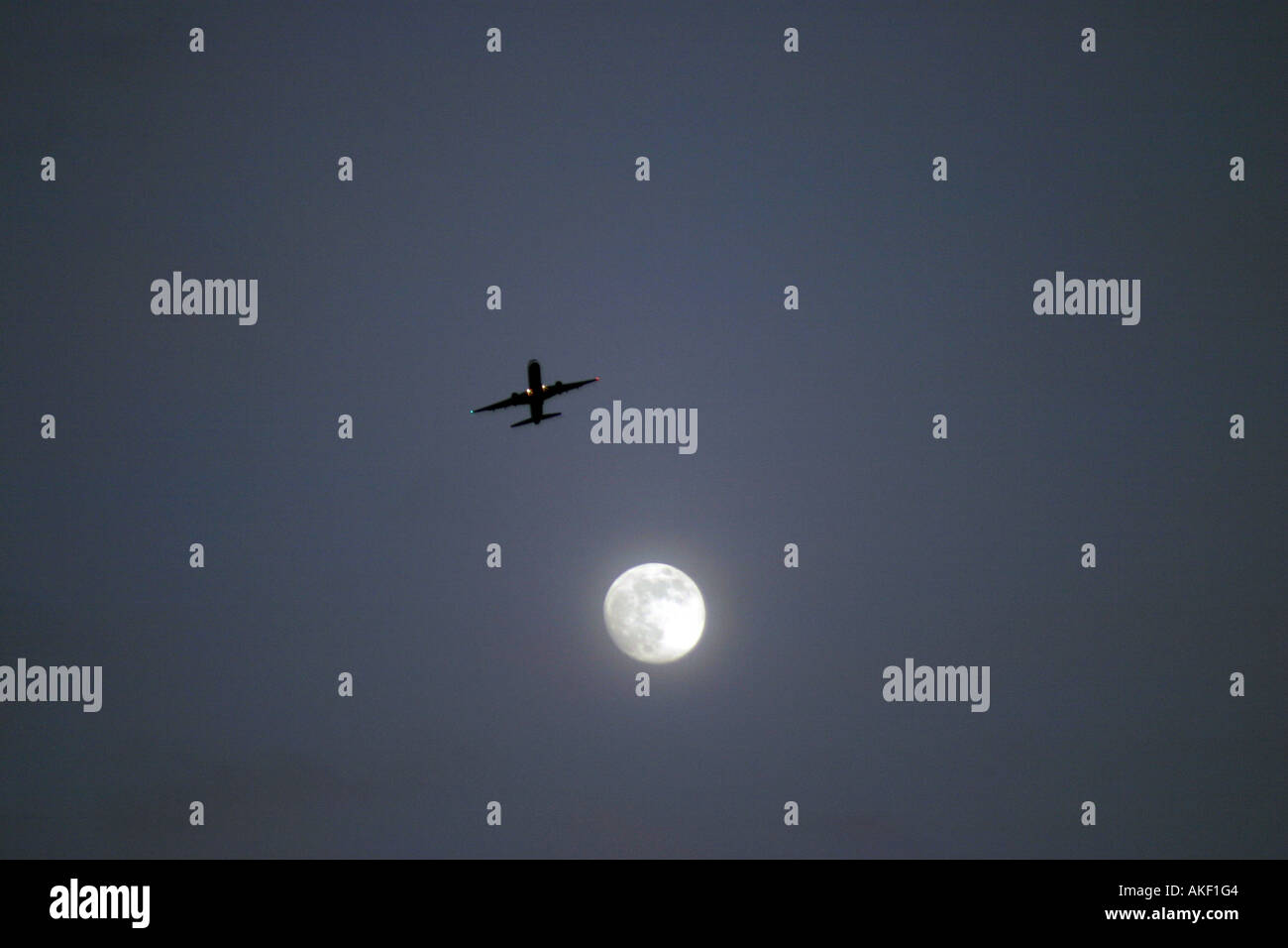 Airplane flying past the moon Stock Photo - Alamy