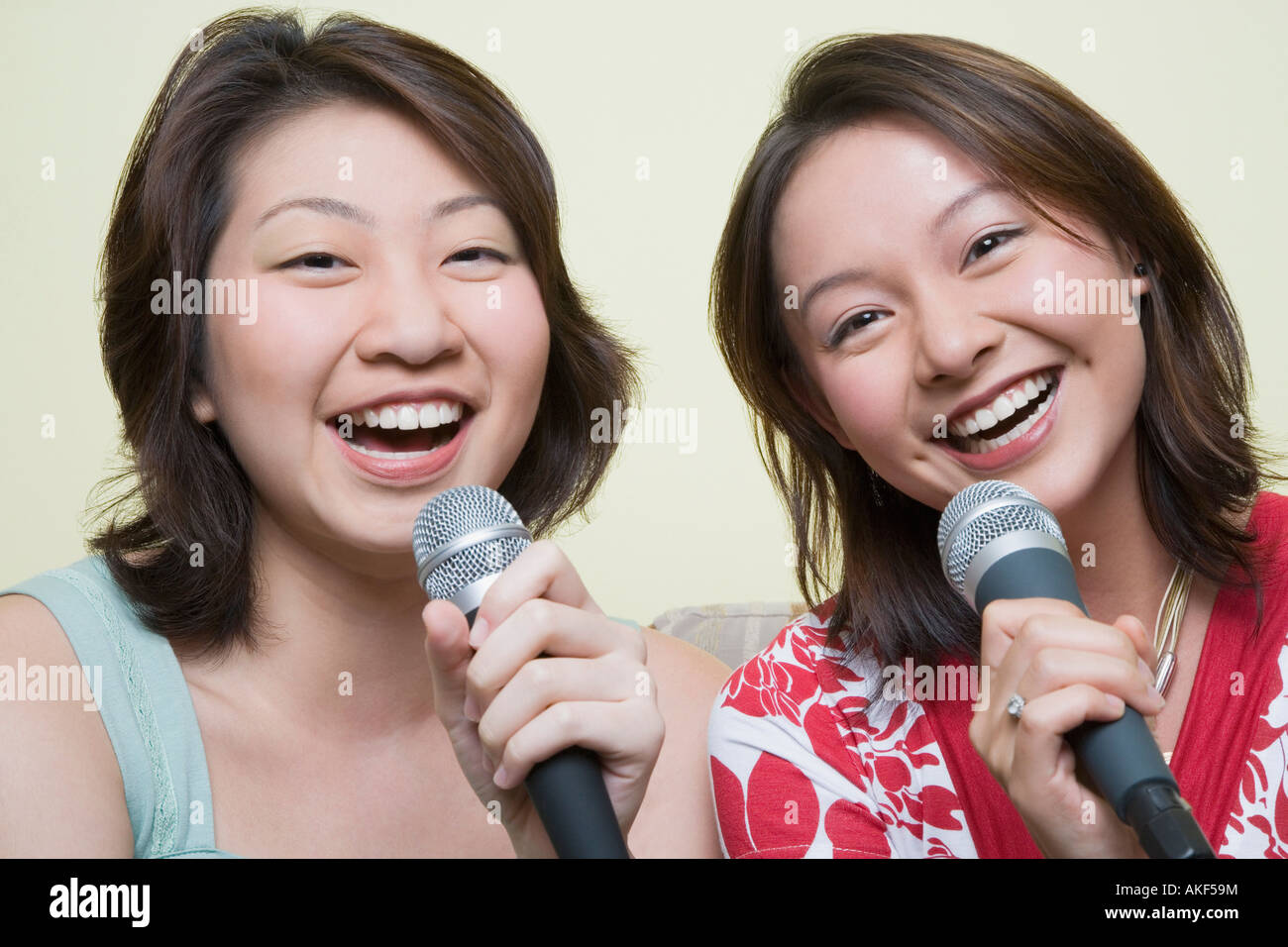Portrait of two young women singing together into microphones Stock ...