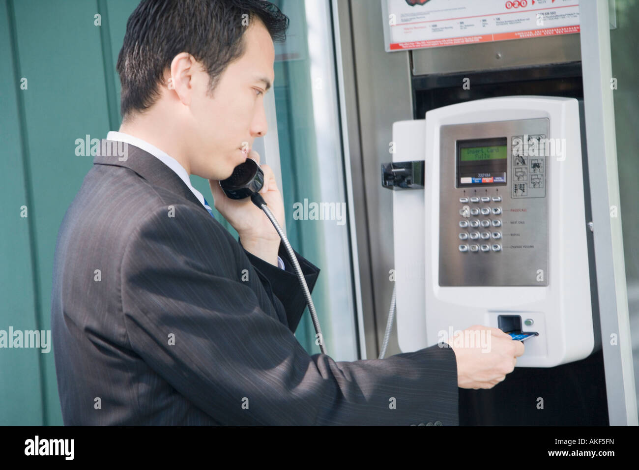 Side profile of a businessman talking on a public phone Stock Photo - Alamy