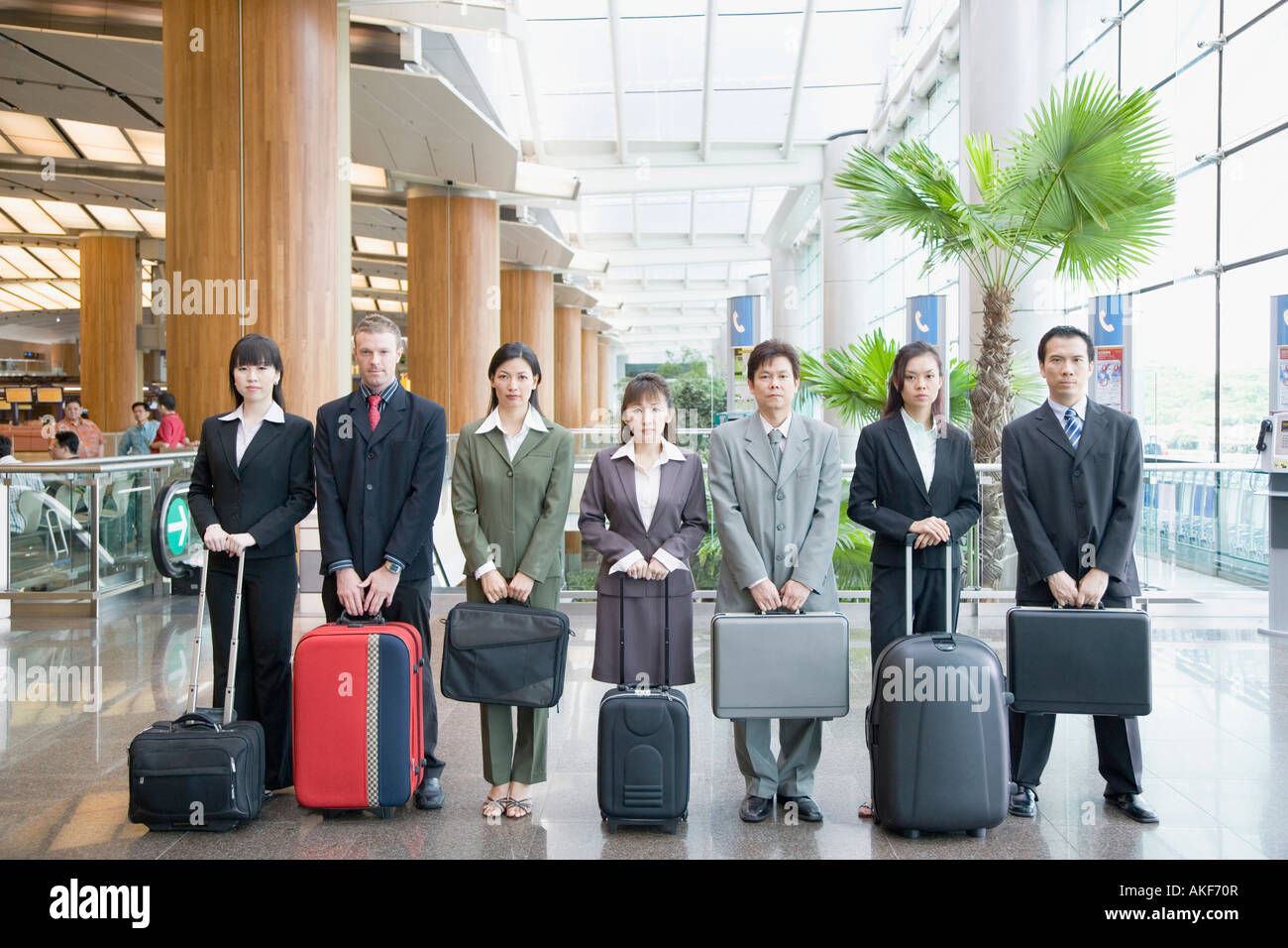 Business executives standing at an airport lounge with their luggage ...