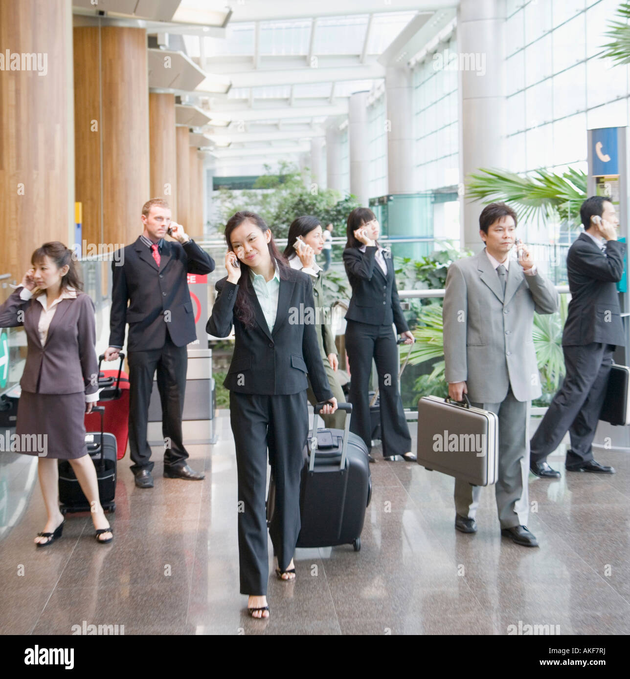 Business executives talking on mobile phones and leaving an airport ...