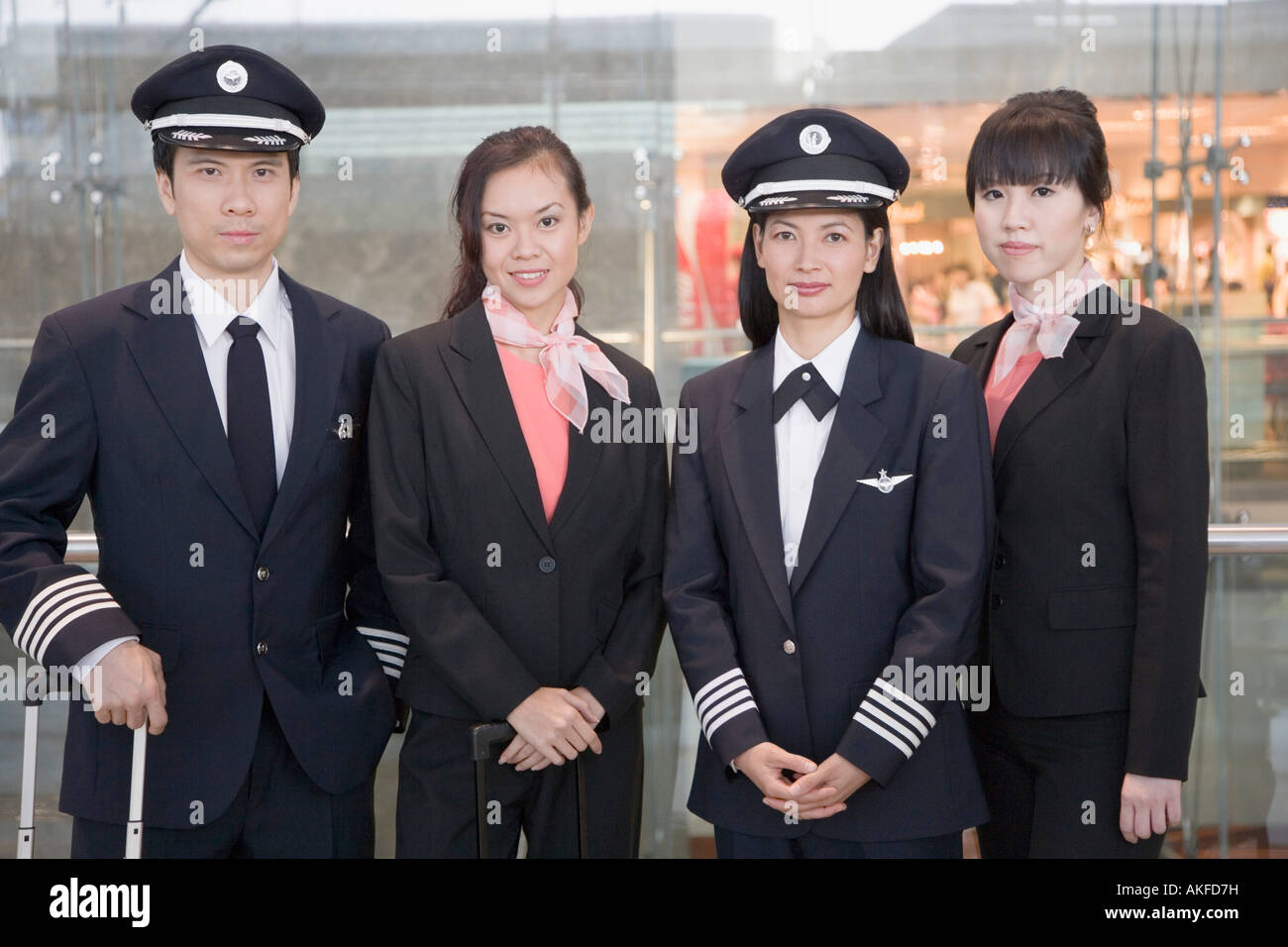 Portrait of a male and a female pilot standing with two female cabin ...