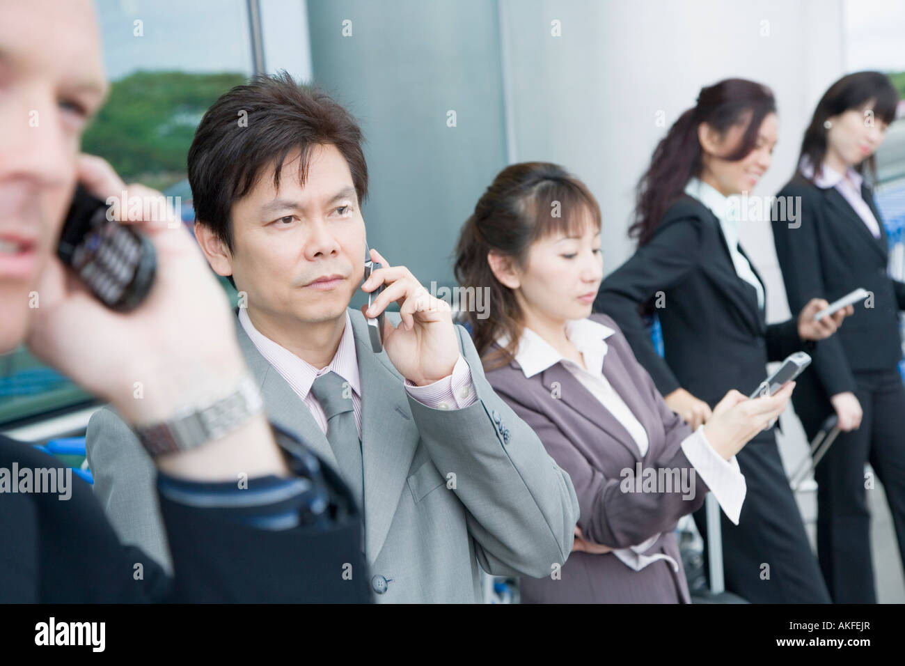 Three businesswomen with two businessmen waiting at an airport lounge ...
