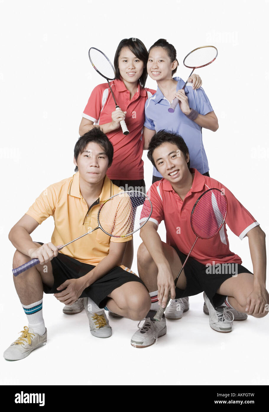 Portrait of two young couples holding badminton rackets and smiling ...