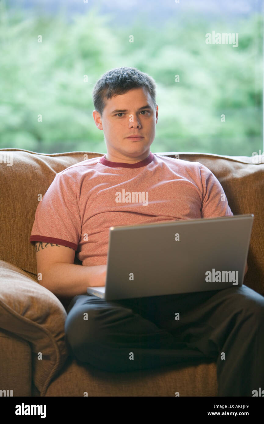 Man sitting on a sofa with a laptop Stock Photo - Alamy