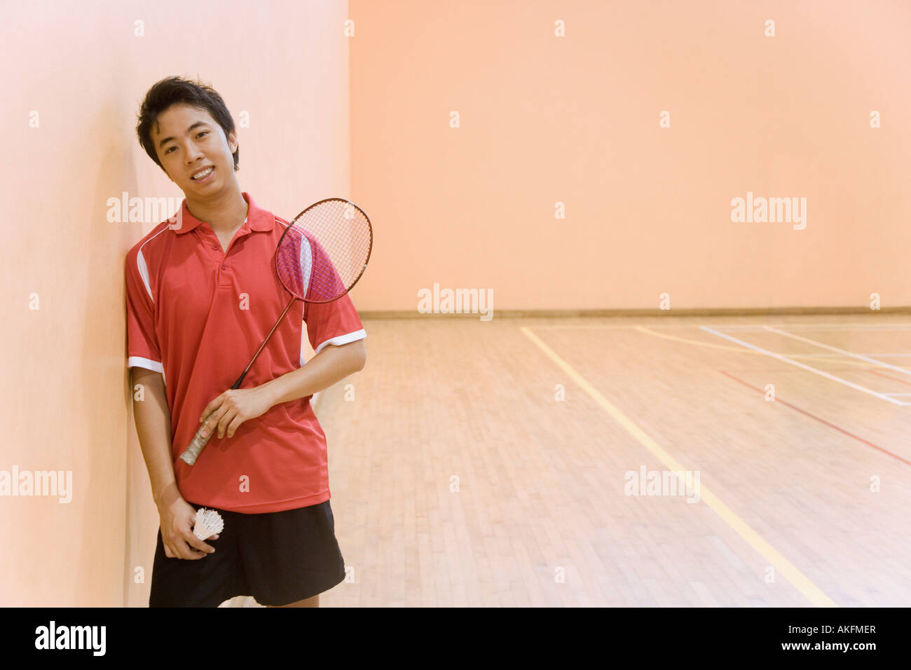 Portrait of a young man holding a badminton racket and a shuttlecock ...