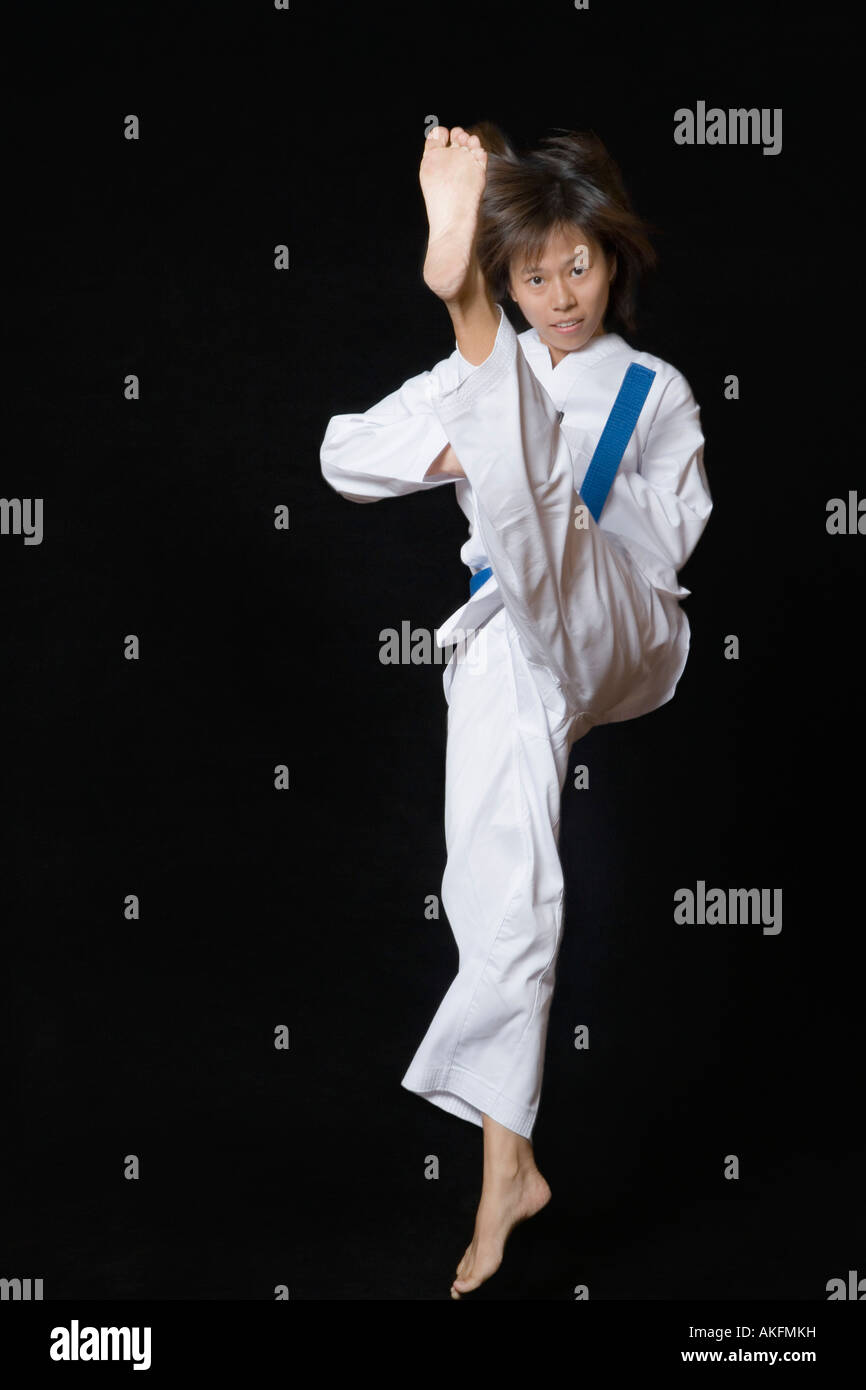 Portrait of a young woman performing front kick Stock Photo - Alamy