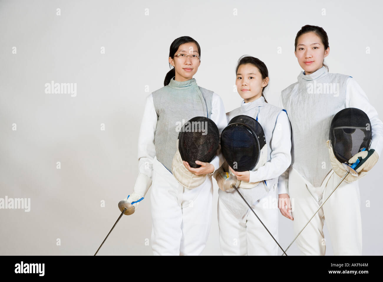 Portrait of three female fencers holding fencing foils and fencing ...