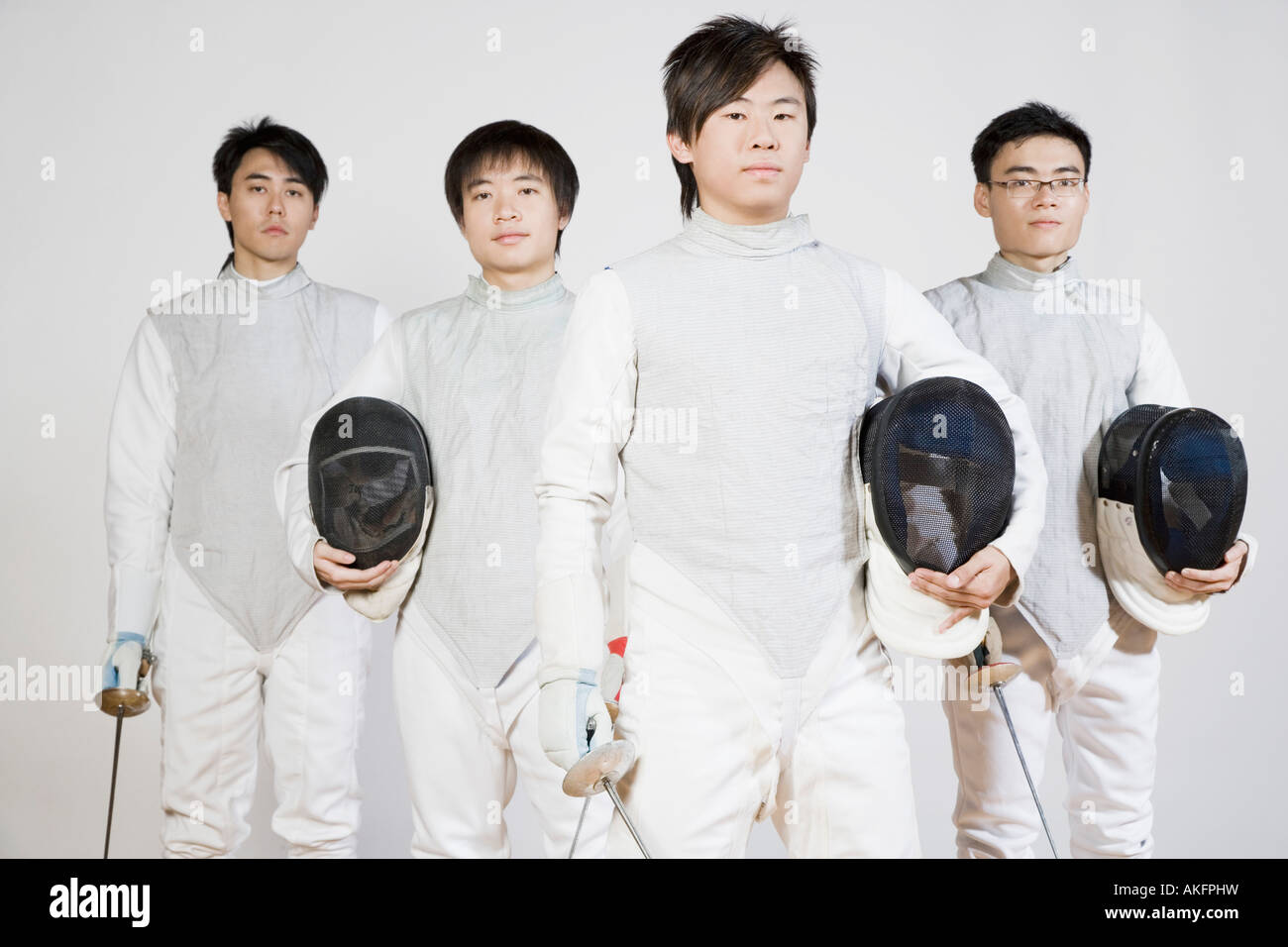 Portrait of four male fencers holding fencing foils and fencing masks ...