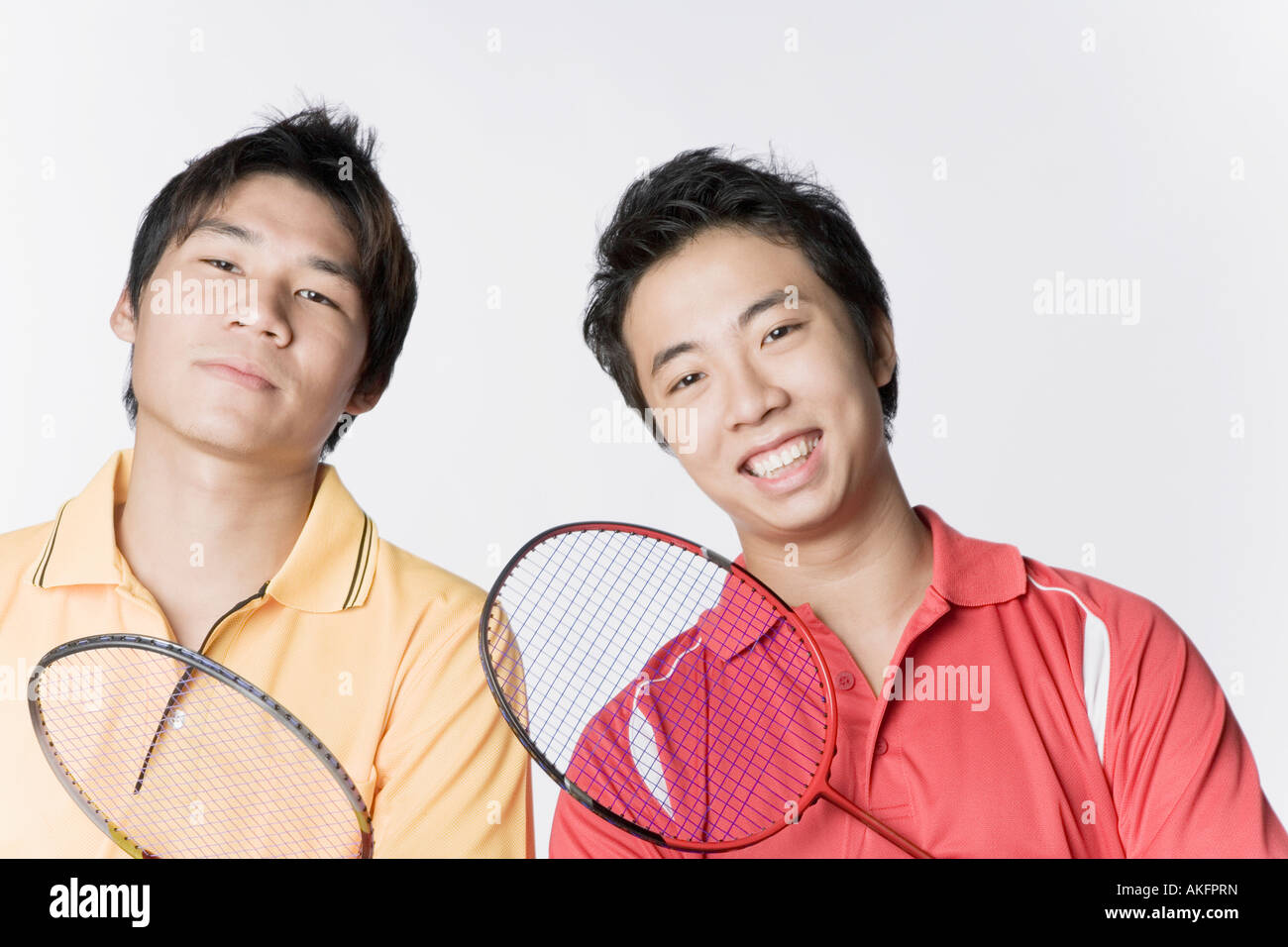 Portrait of two young men holding badminton rackets and smiling Stock ...