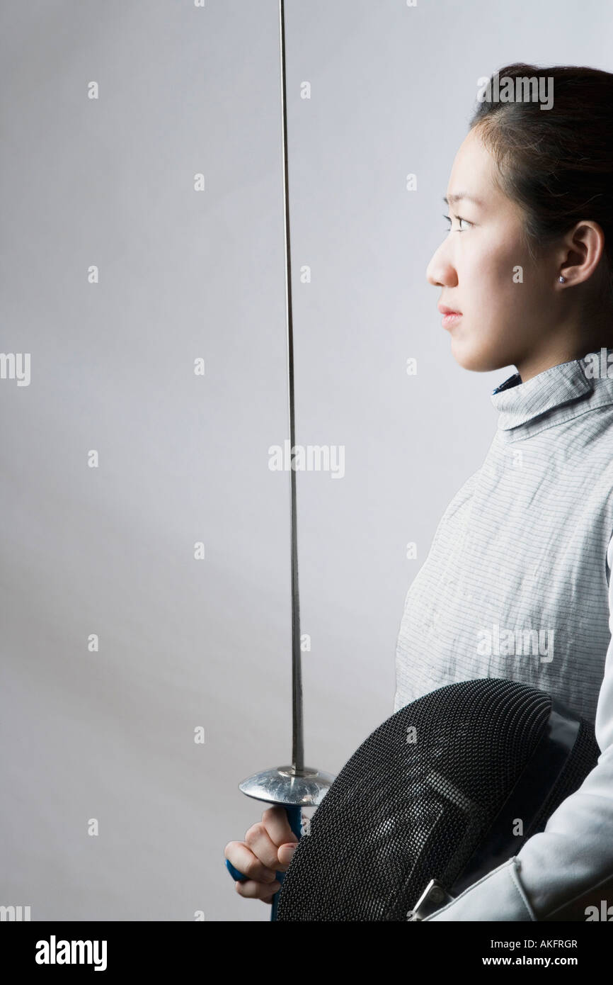 Side profile of a female fencer holding a sword and a fencing mask Stock Photo - Alamy