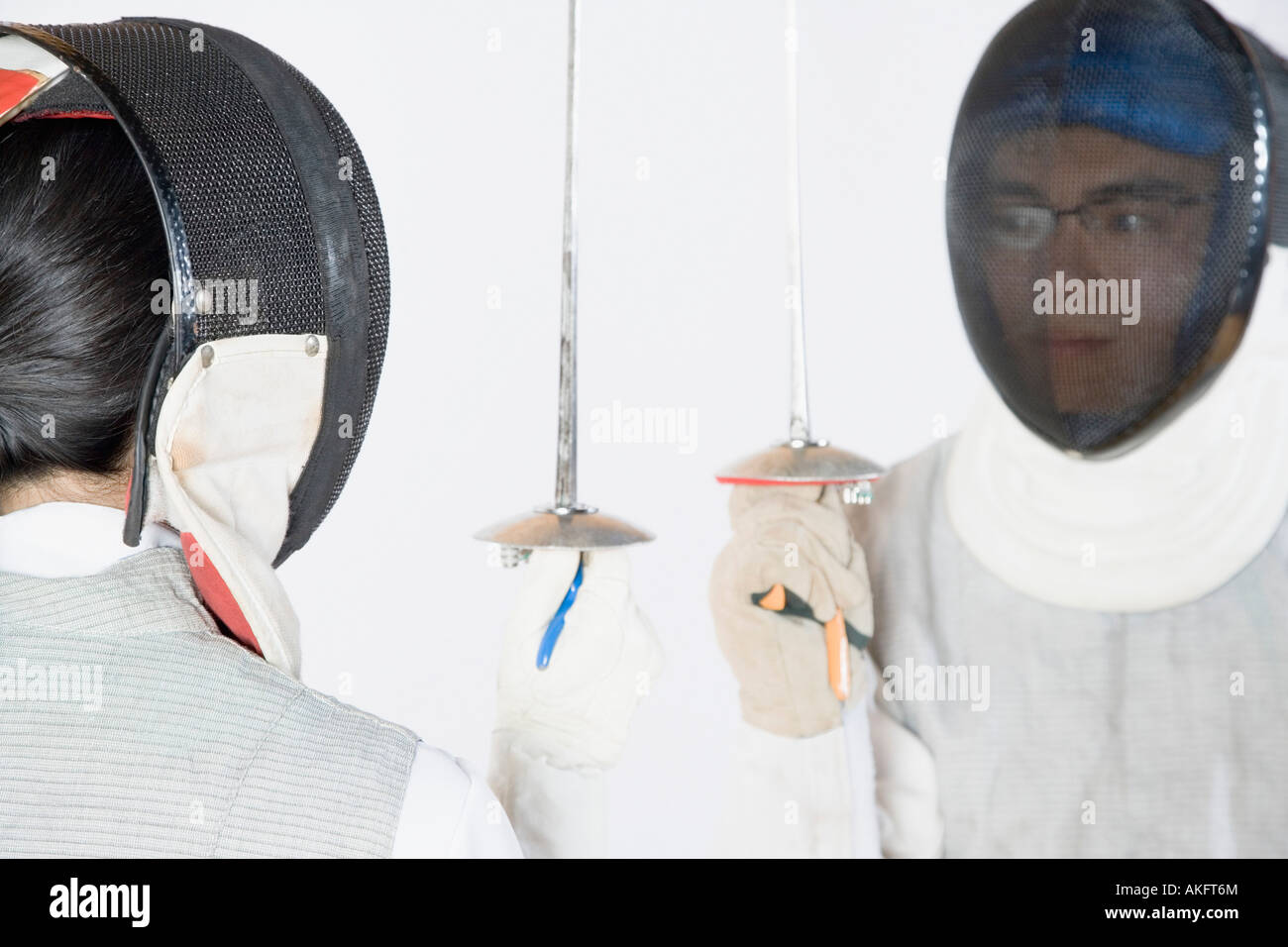 Close-up of two people wearing fencing masks and holding fencing foils ...