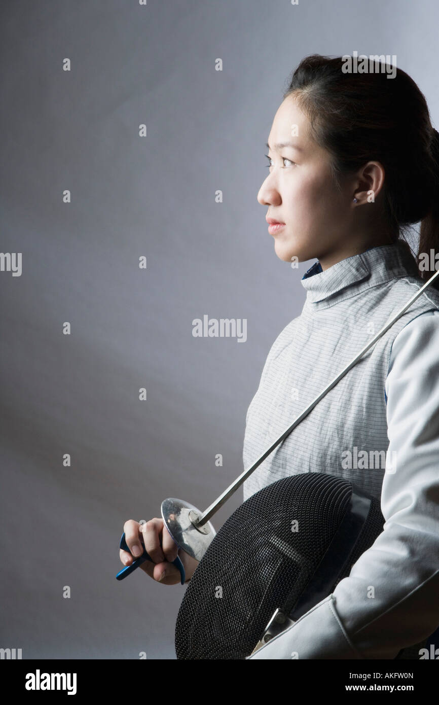 Side profile of a female fencer holding a sword and a fencing mask Stock Photo - Alamy