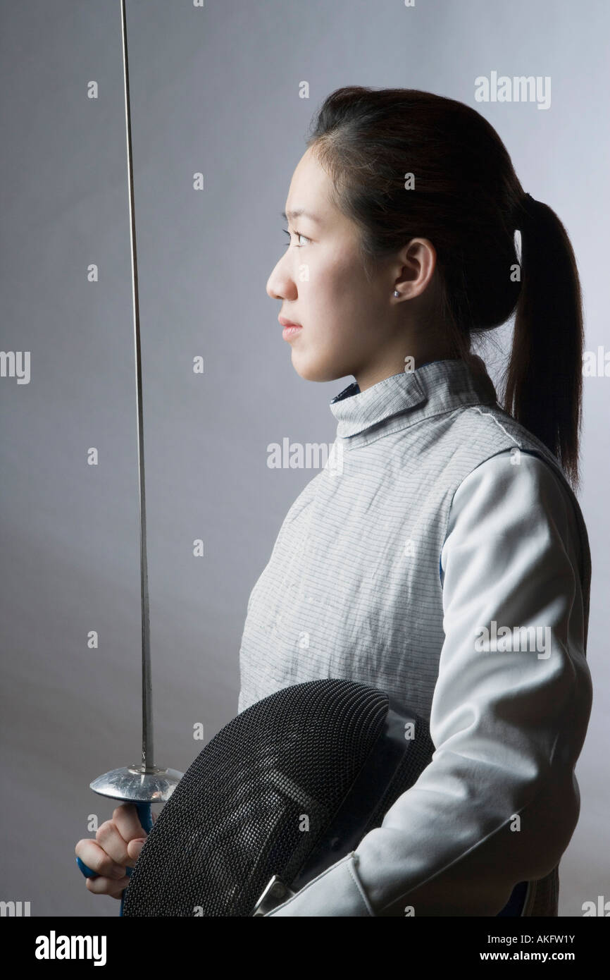 Side profile of a female fencer holding a sword and a fencing mask Stock Photo - Alamy