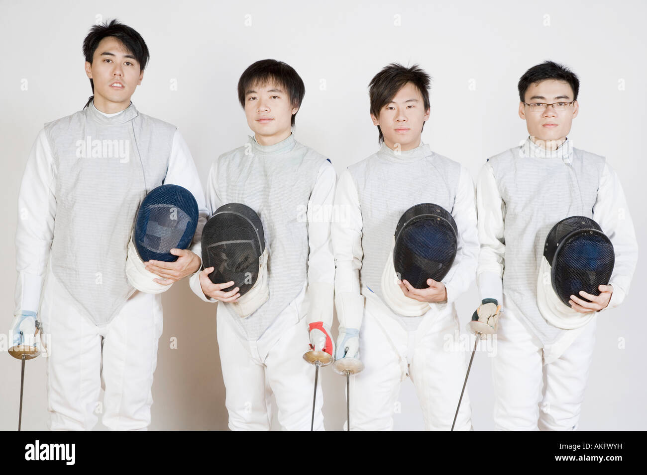 Portrait of four male fencers holding fencing foils and fencing masks ...