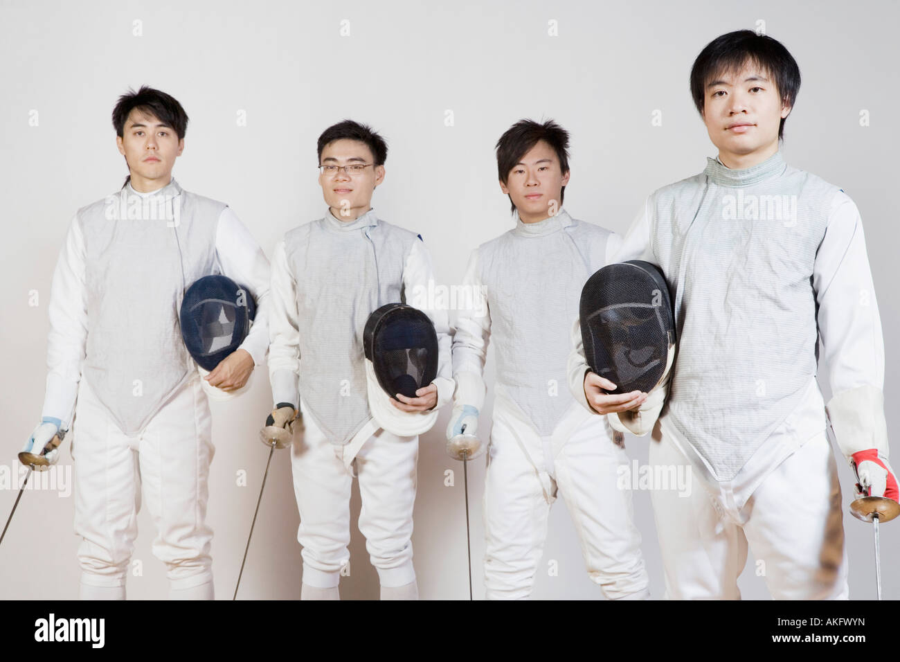 Portrait of four male fencers holding fencing foils and fencing masks ...