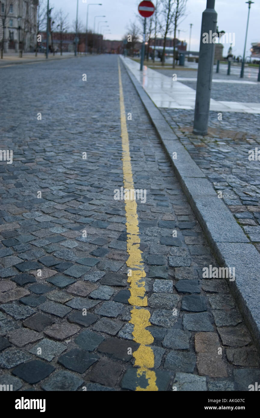 Single yellow line on cobble street Stock Photo - Alamy