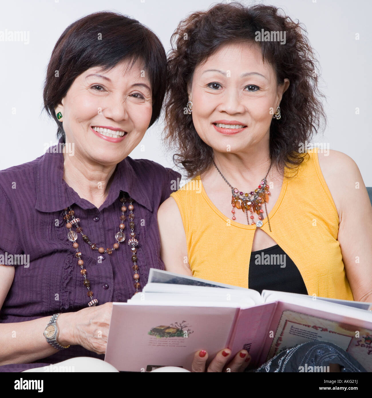 Portrait of two senior women sitting with a photo album and smiling ...