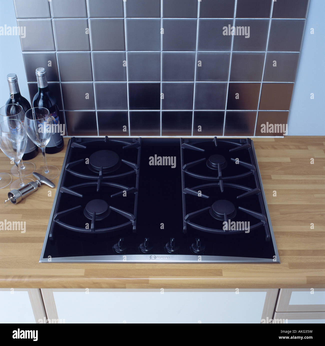 Stainless steel tiles behind black gas hob in modern kitchen Stock ...