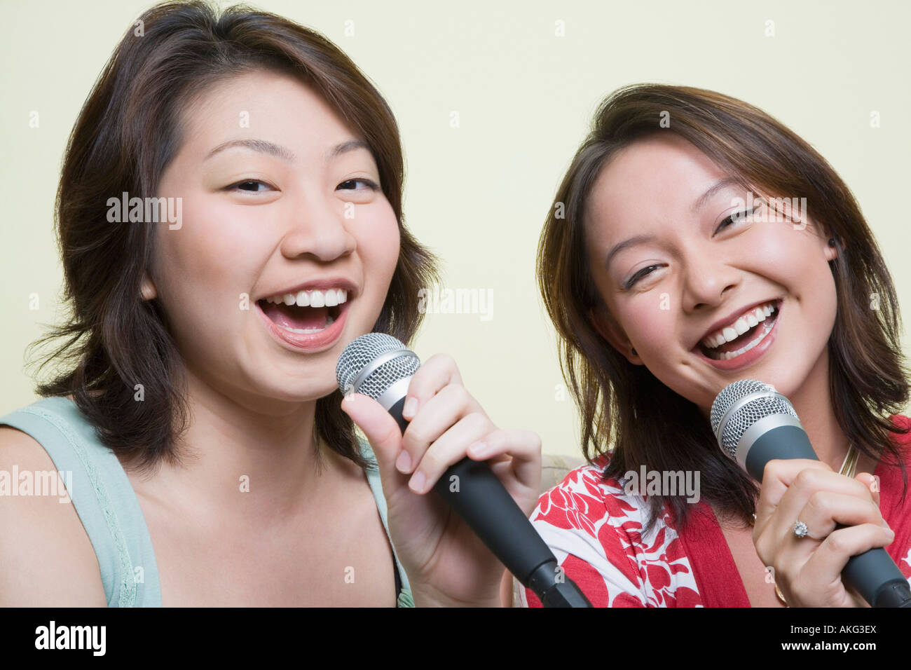 Portrait of two young women singing together into microphones Stock ...