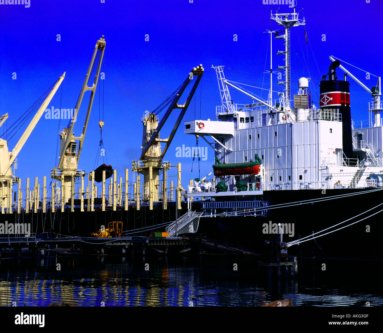 Ocean going freighter Mercury Island takes on logs in the calm harbor ...