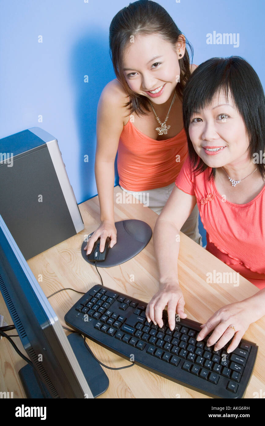 Portrait of a young woman and her mother using a computer and smiling ...