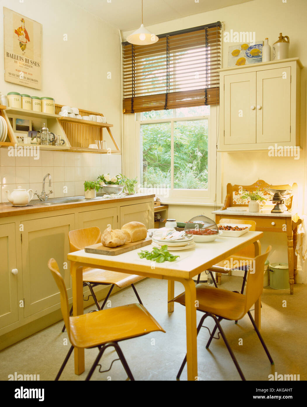 Cream country kitchen with slatted wooden blind at window and loaves of ...