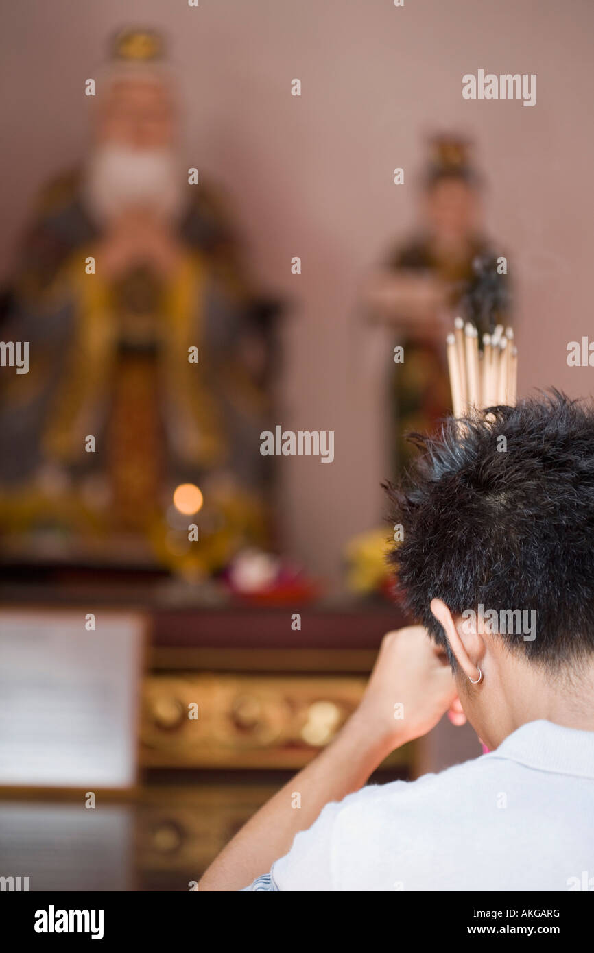 Rear view of a young man praying in a temple Stock Photo - Alamy