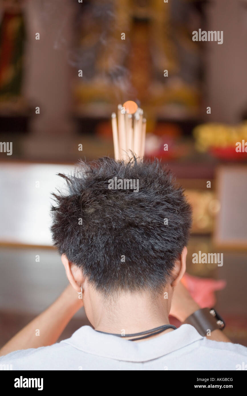 Rear view of a young man praying in a temple Stock Photo - Alamy