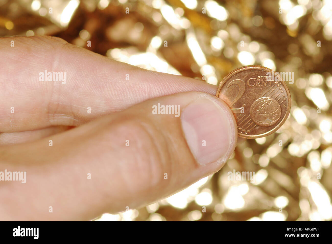 Hand holding coin in front of gold Stock Photo - Alamy