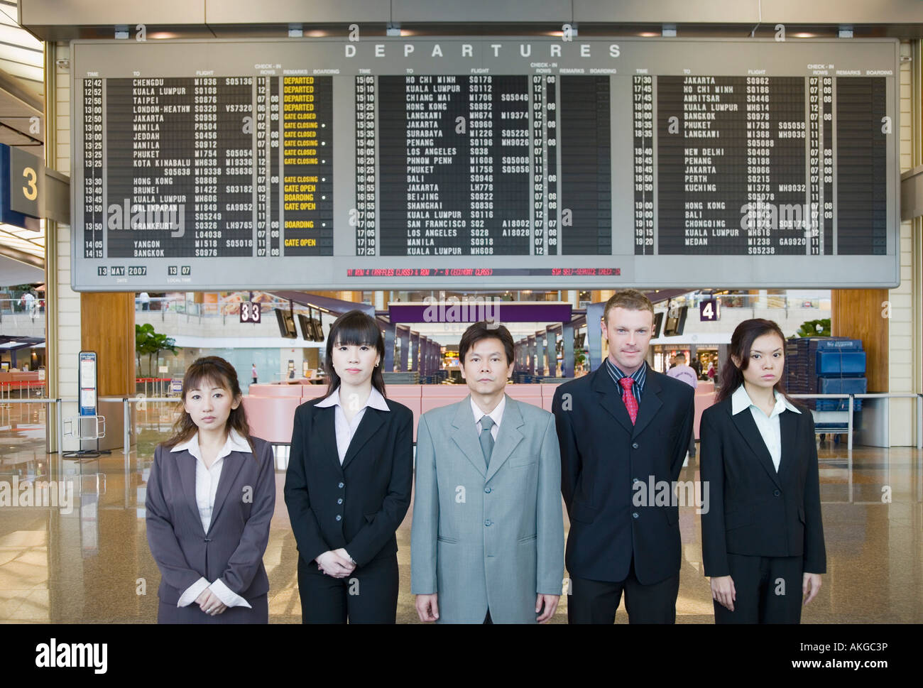 Portrait of five business executives standing in front of an arrival ...