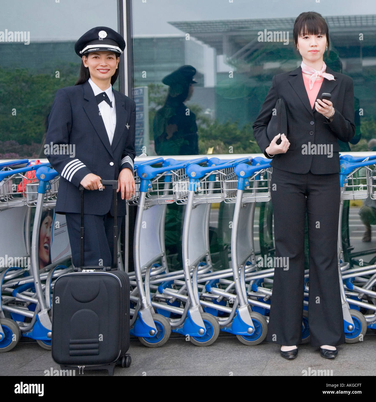 Portrait of a female cabin crew holding a mobile phone and standing ...
