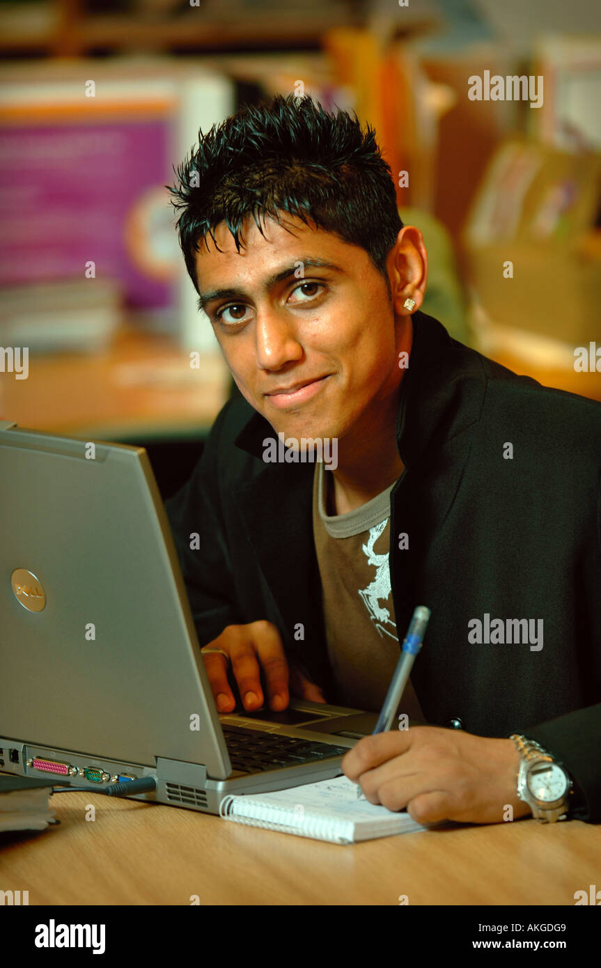 A TEENAGE BOY WORKING ON A LAPTOP COMPUTER IN AN OFFICE ENVIRONMENT UK ...