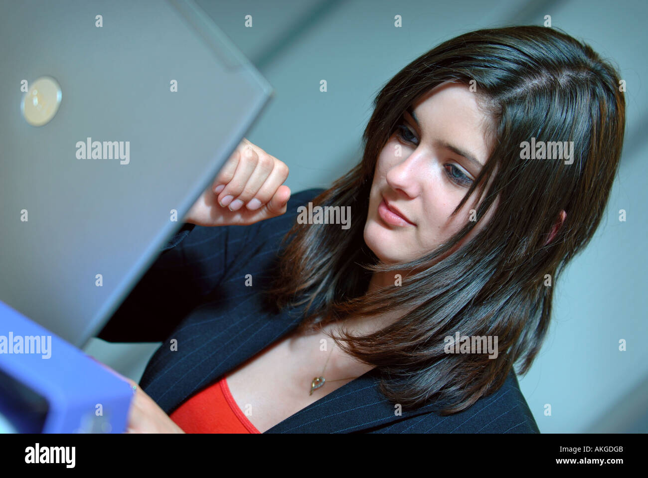 A TEENAGE GIRL WORKING ON A LAPTOP COMPUTER IN AN OFFICE ENVIRONMENT UK ...