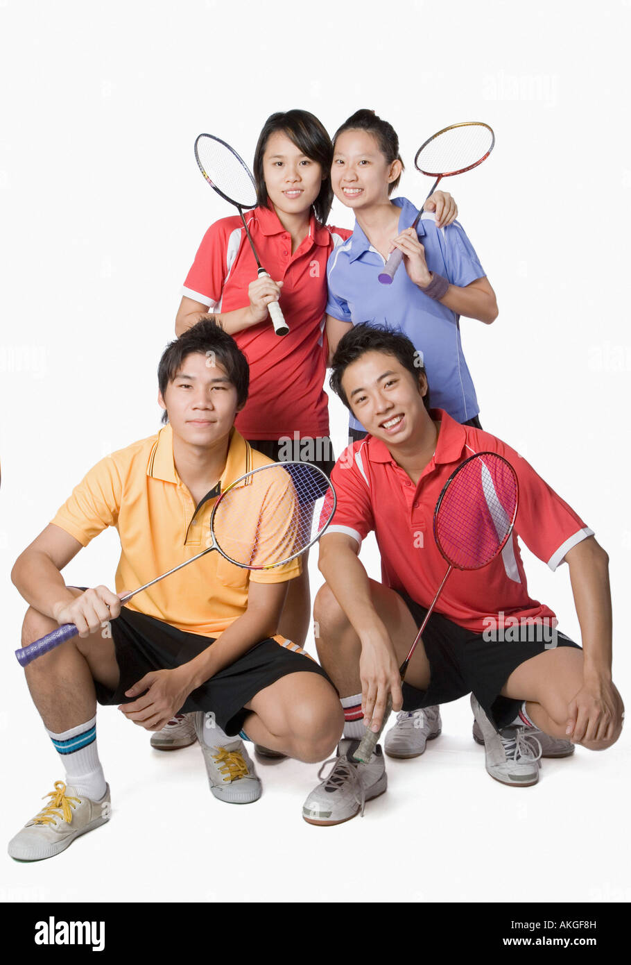 Portrait of two young couples holding badminton rackets and smiling ...