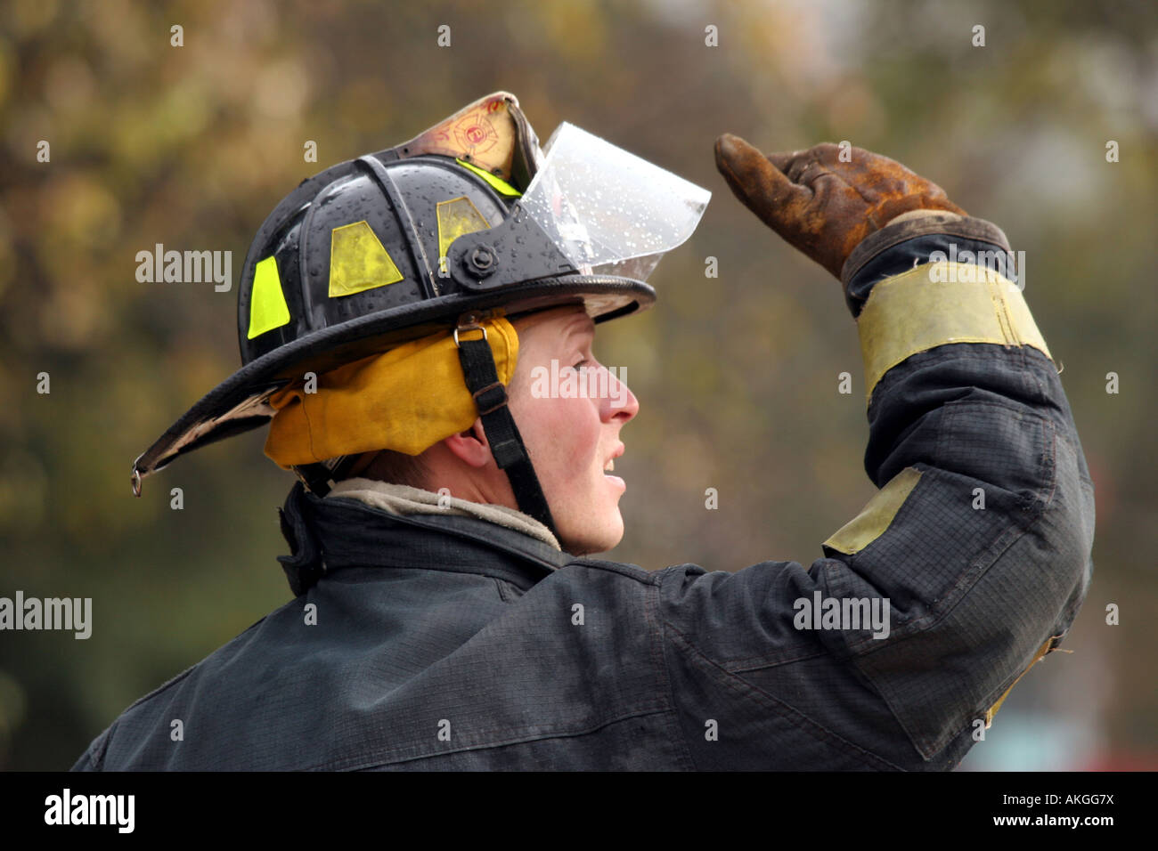 A firefighter shielding her eyes from the sun at an emergency scene ...