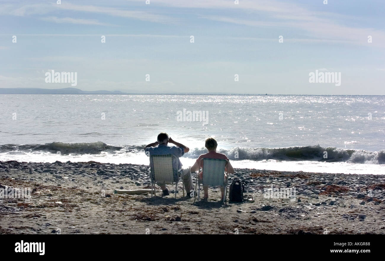 Couple sitting in sun on the beach at Clarach Bay Wales Stock Photo - Alamy