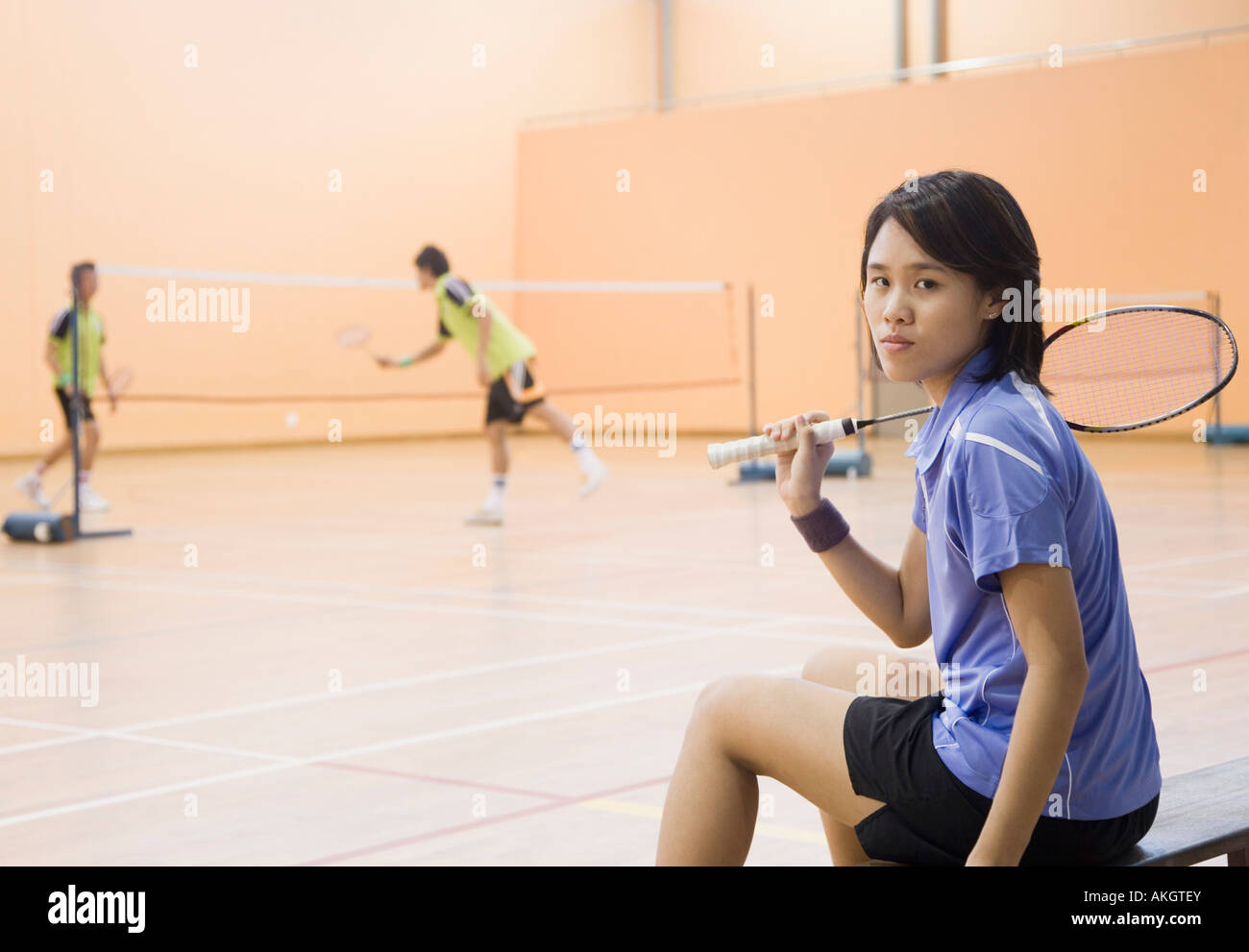 Portrait of a young woman sitting on a bench and holding a badminton ...