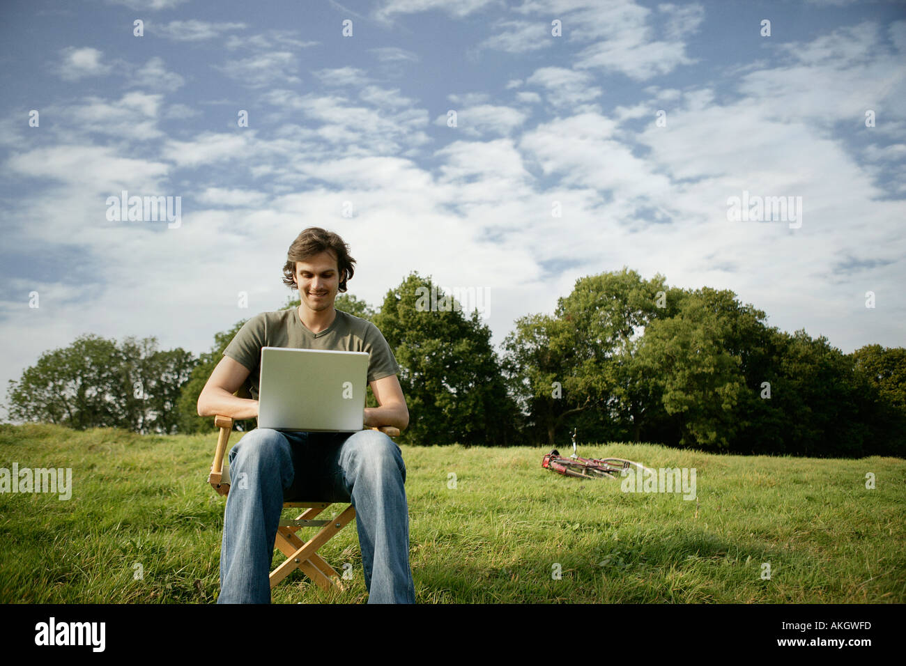 Man sitting on grassy meadow using laptop computer Stock Photo - Alamy