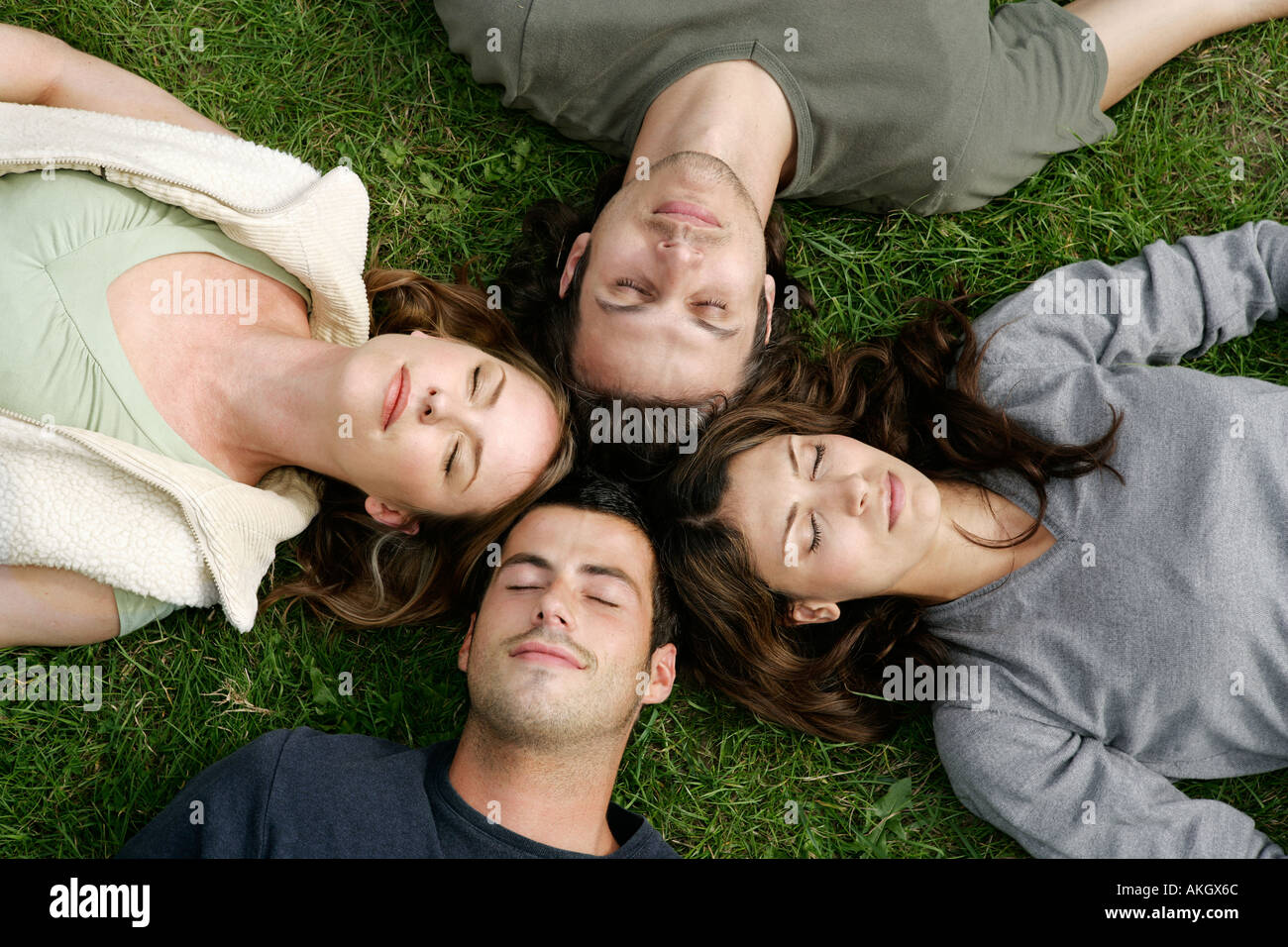 Group of four with heads together lying on grass Stock Photo - Alamy