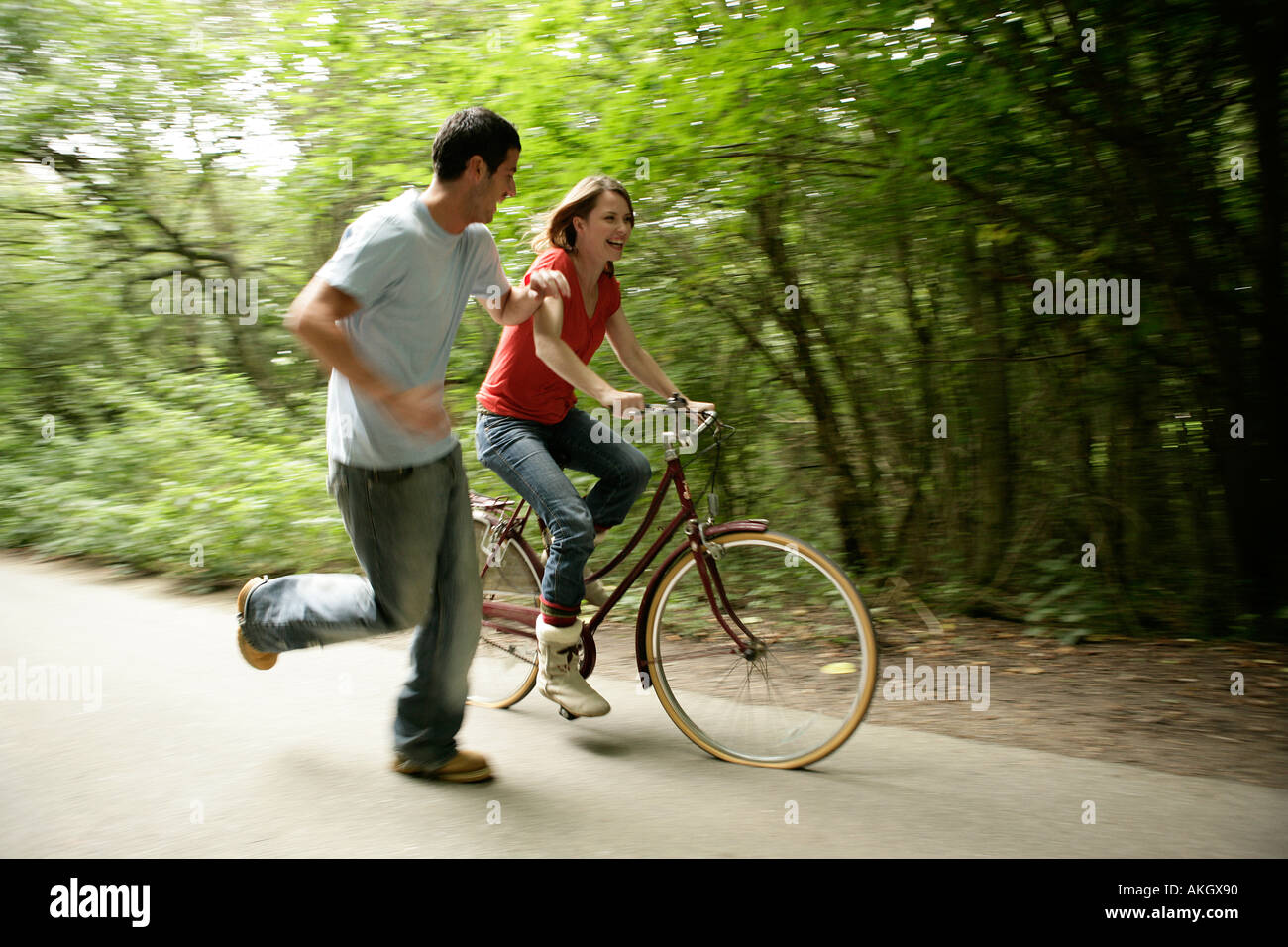 Woman riding on bicycle with man running alone side Stock Photo - Alamy